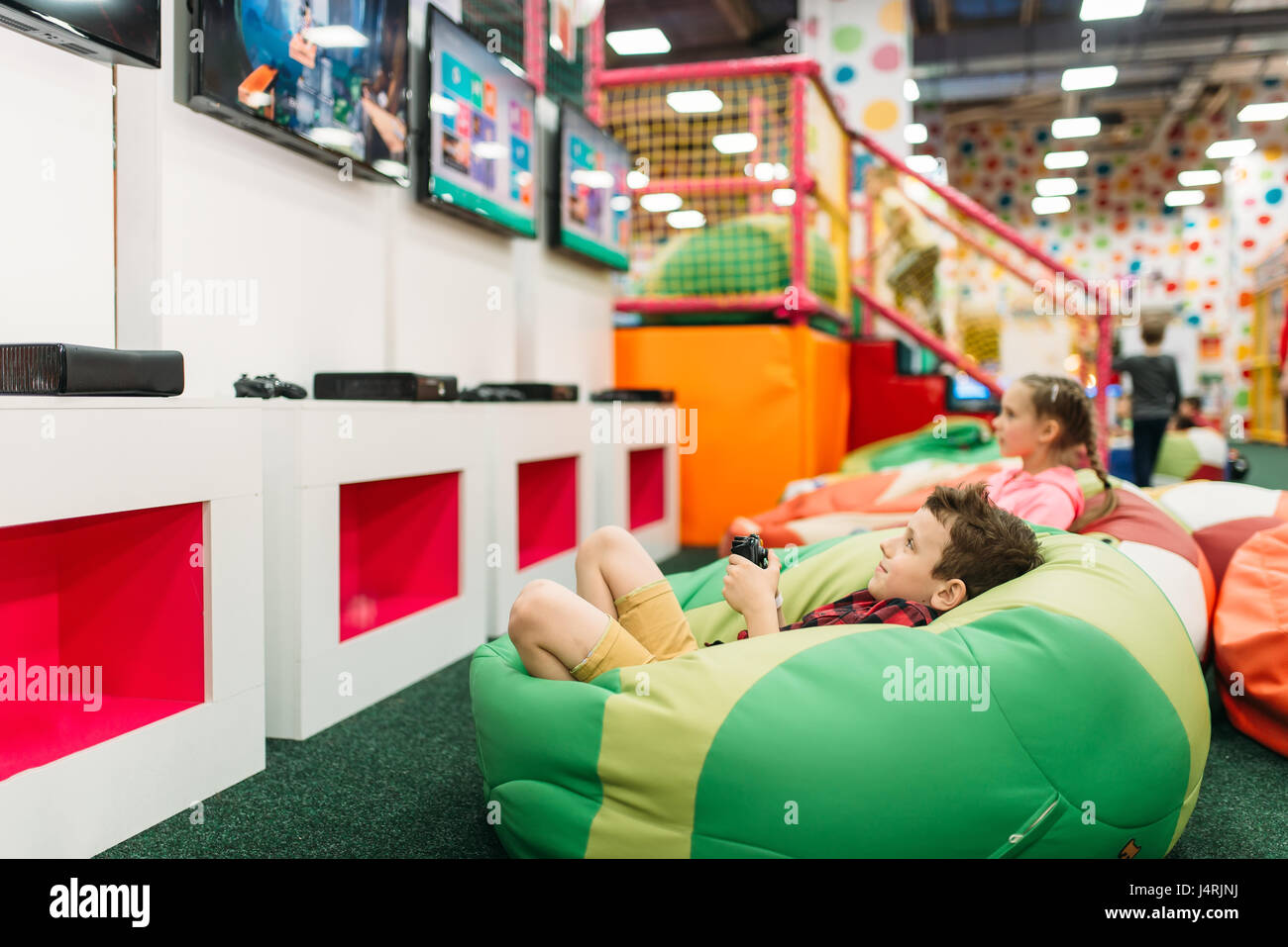 Smiling kids play in a games console in childrens entertainment center ...
