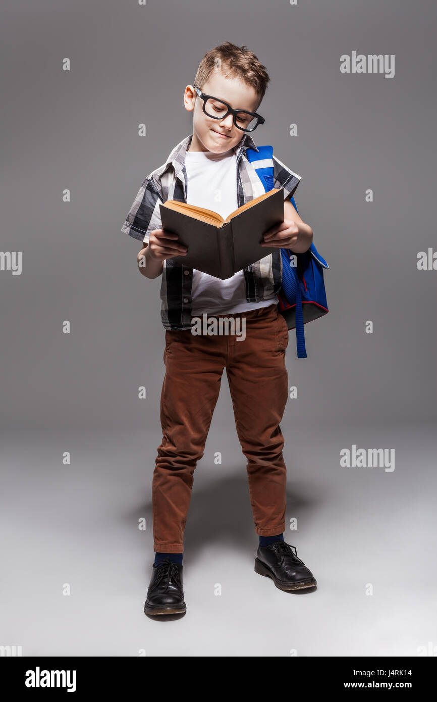Little child with school bag and book, studio photo shoot. Young pupil ...