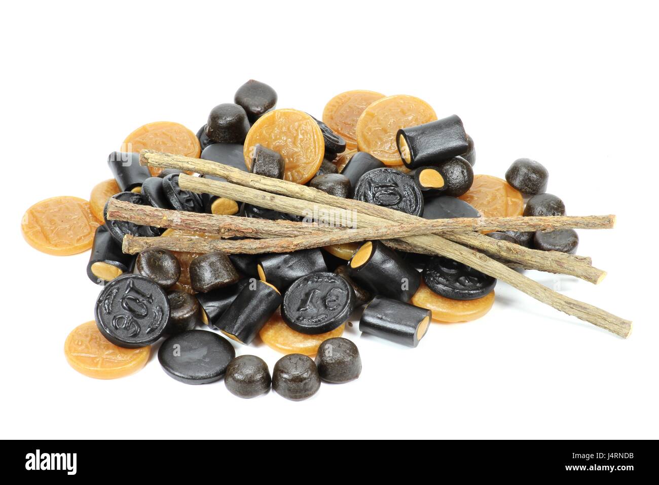 licorice candies with dried sticks of licorice root isolated on white ...