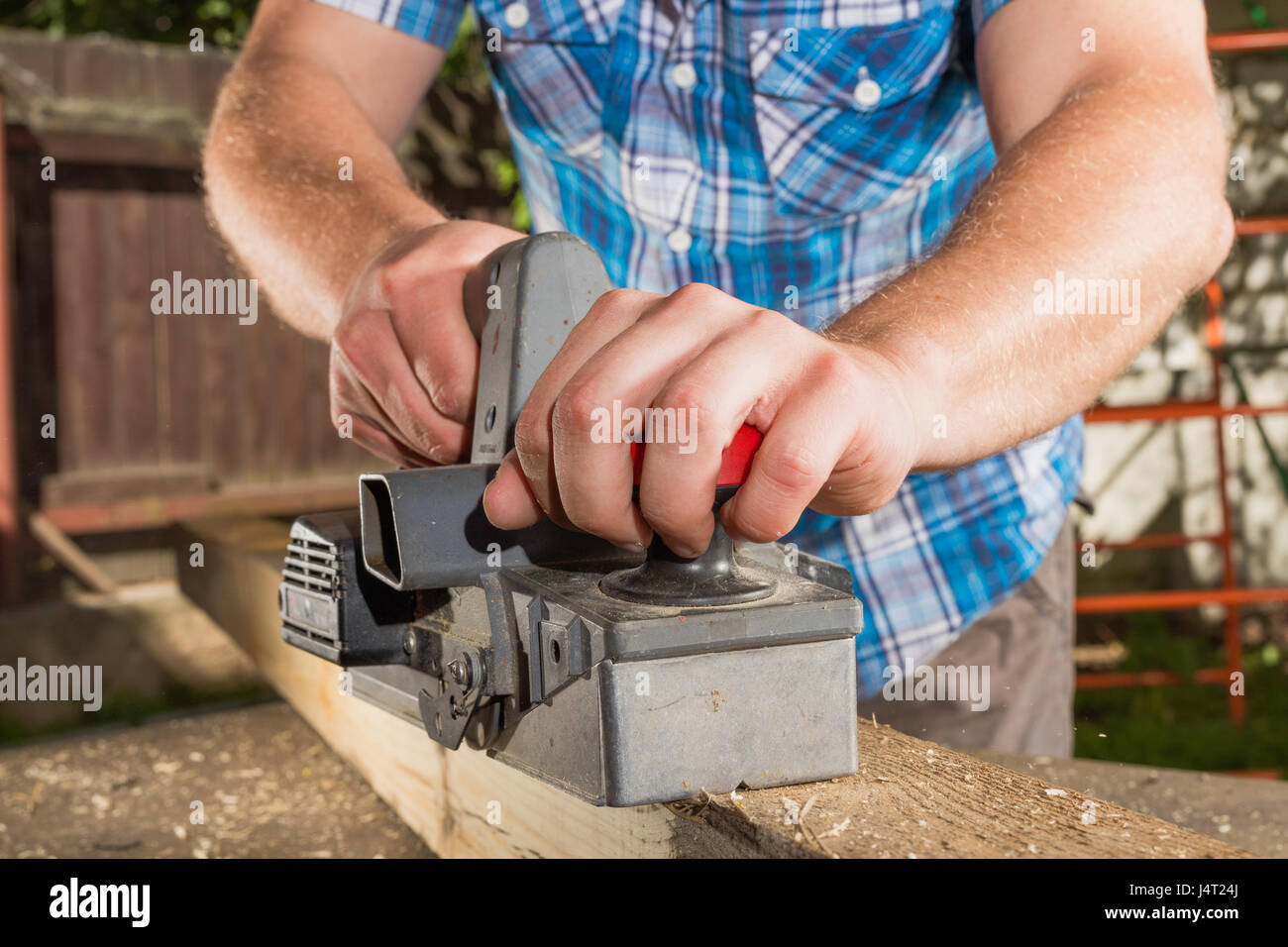 Carpenter chipping the wooden plank by the electric plane Stock Photo ...
