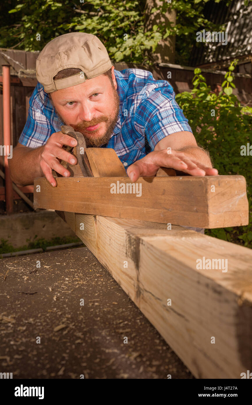 Carpenter chipping the wooden plank by the plane Stock Photo - Alamy