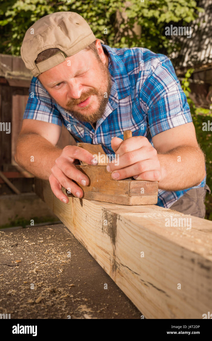 Carpenter chipping the wooden plank by the plane Stock Photo - Alamy
