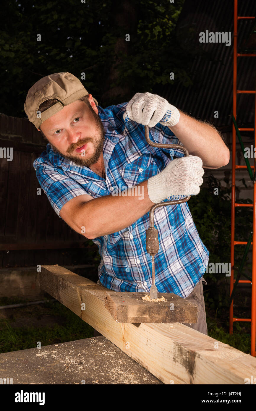 Carpenter working by hand drill on natural background Stock Photo - Alamy