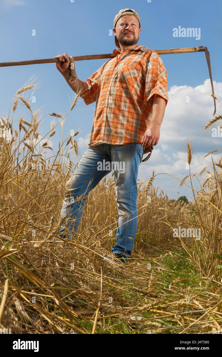 Modern farmer with scythe at ripe wheat field Stock Photo - Alamy