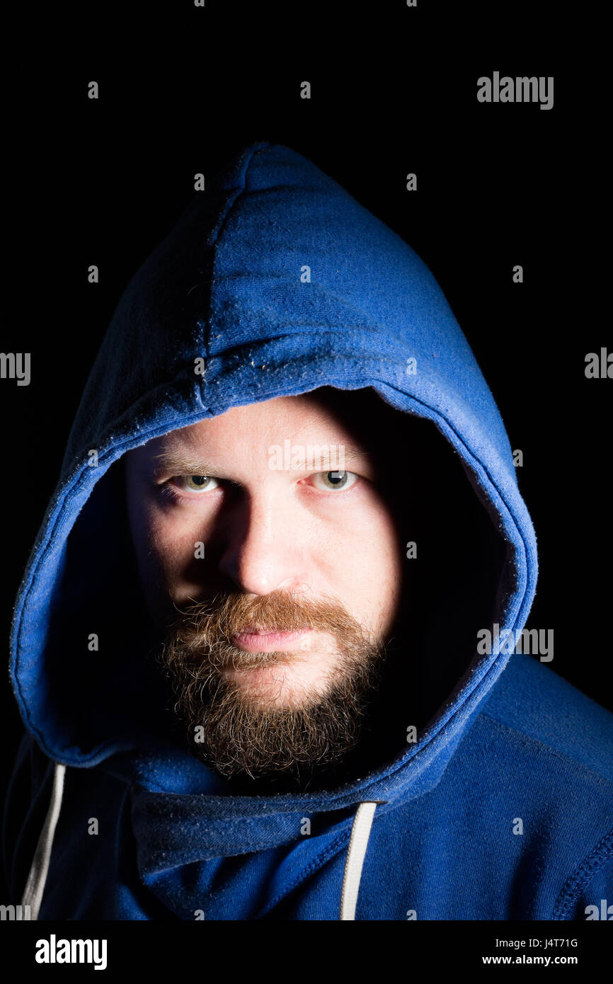 Solid bearded middle-aged man in a hood portrait on black background ...