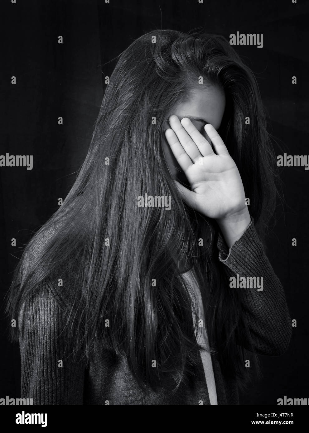 Monochrome close up portrait of young beautiful girl closing her face ...