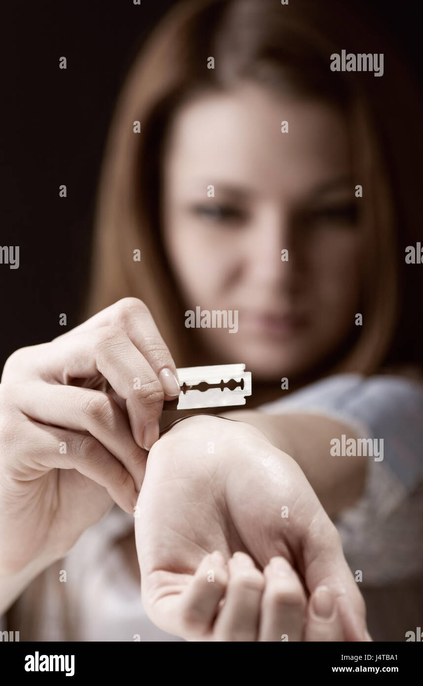 Young woman cuts veins on a hand on a dark background. Focus on hand ...