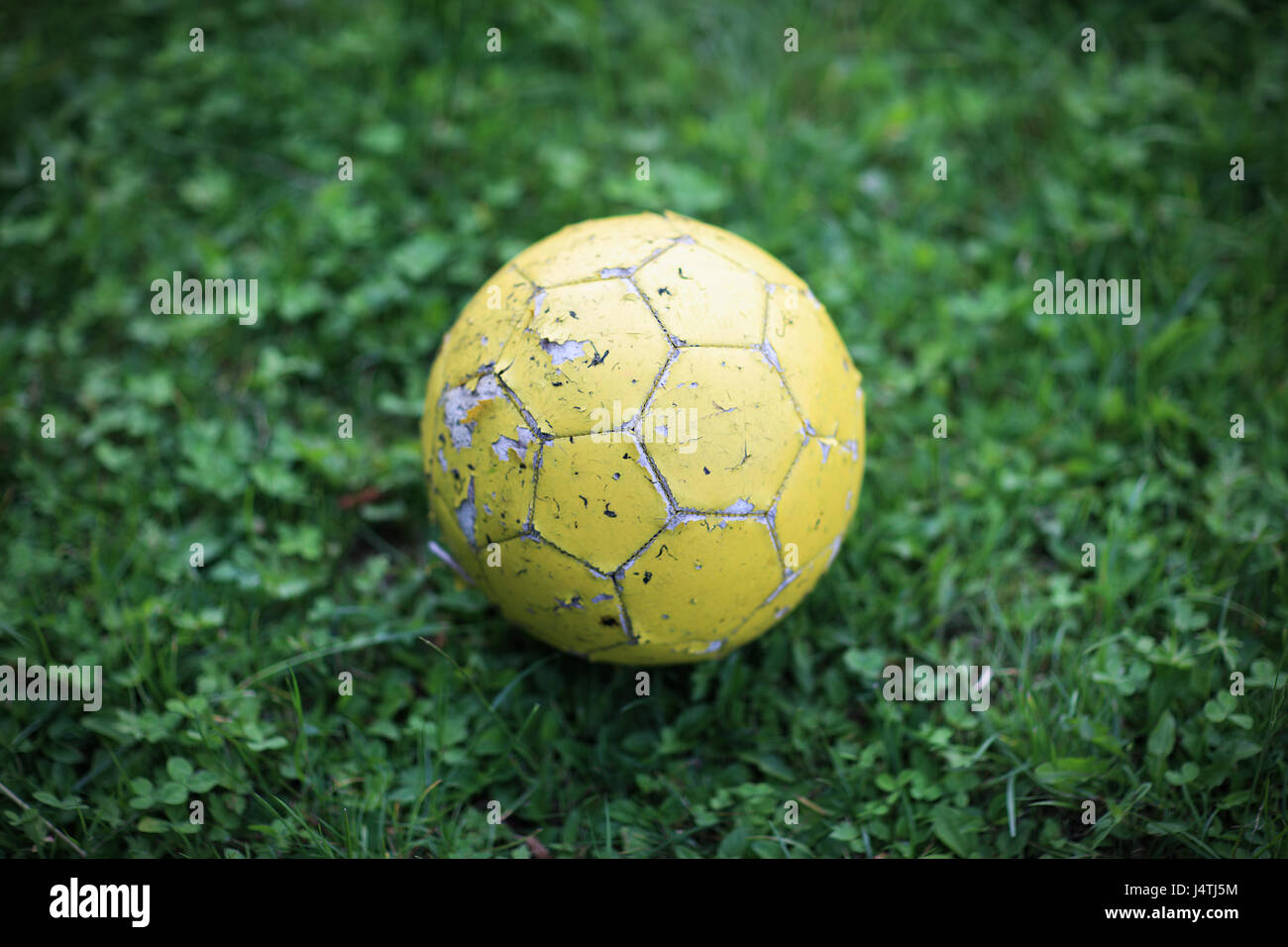 Old yellow soccer ball on green grass Stock Photo - Alamy