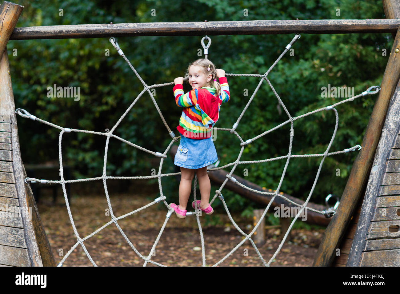 Active little child playing on climbing net and jumping on trampoline ...