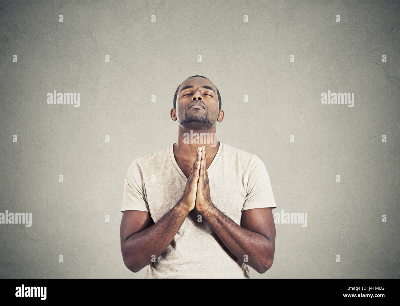 Closeup portrait young man praying hands clasped hoping for best asking ...
