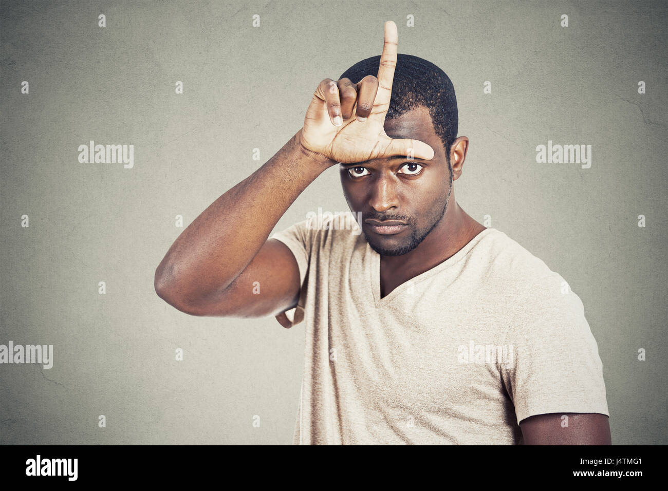 Closeup portrait serious young man showing loser sign on forehead ...