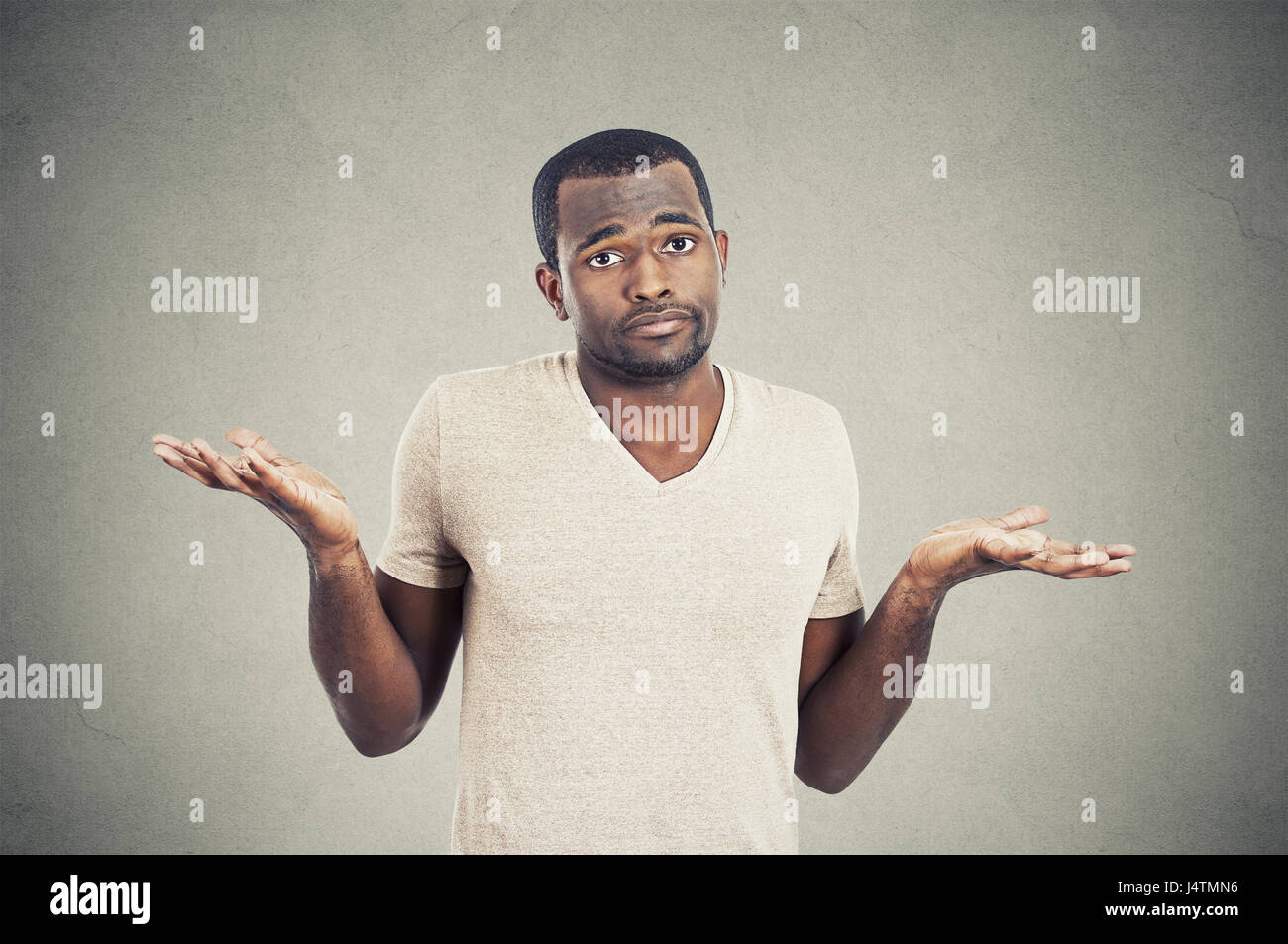 Young man shrugging shoulders who cares so what I don't know gesture ...