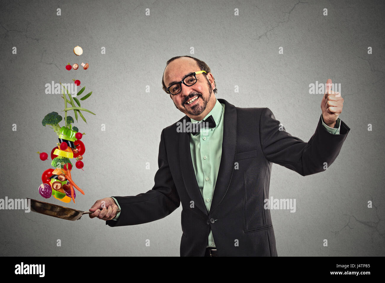 Businessman cooking vegetables with a pan showing thumbs up isolated on ...