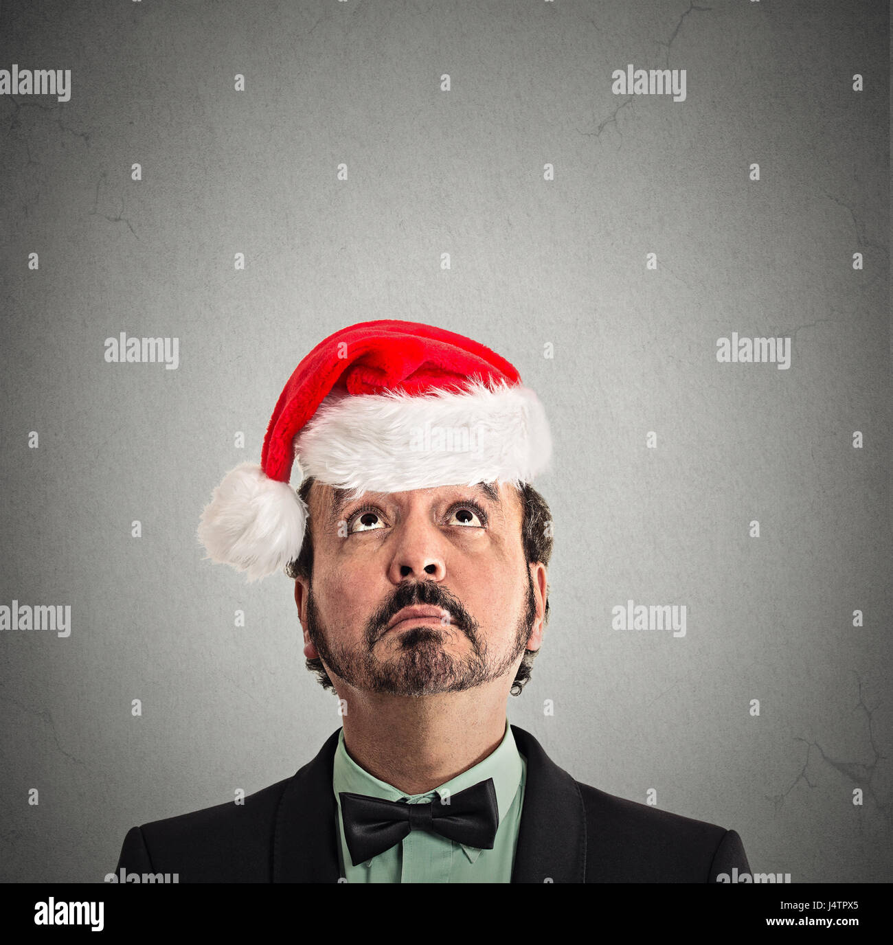 closeup headshot xmas man with red santa claus hat looking up at copy ...