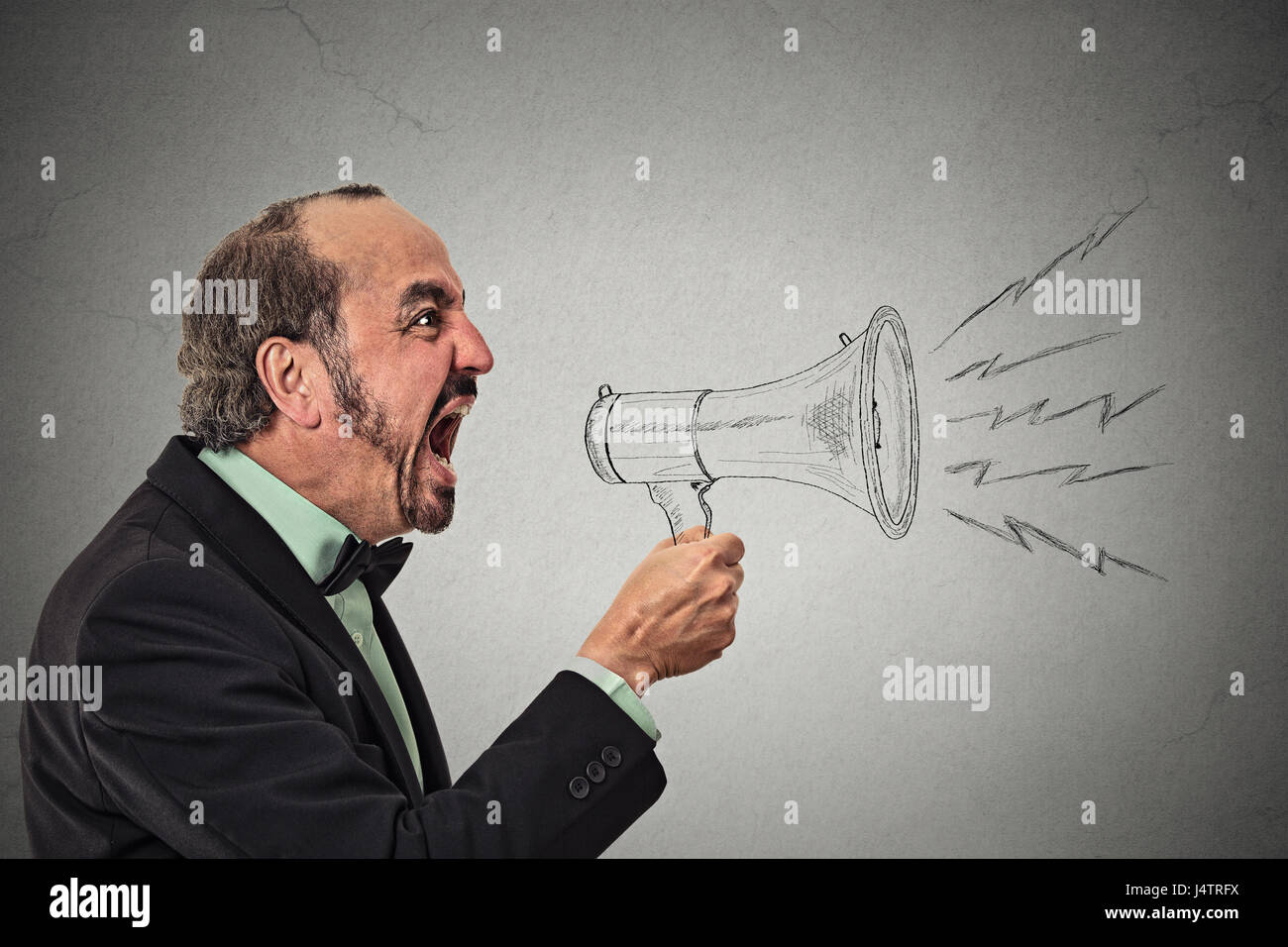 Angry screaming man holding megaphone isolated on grey wall background ...