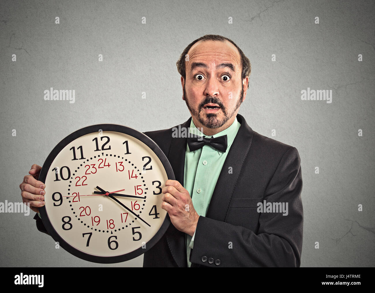 portrait surprised business man in suit holding wall clock isolated ...