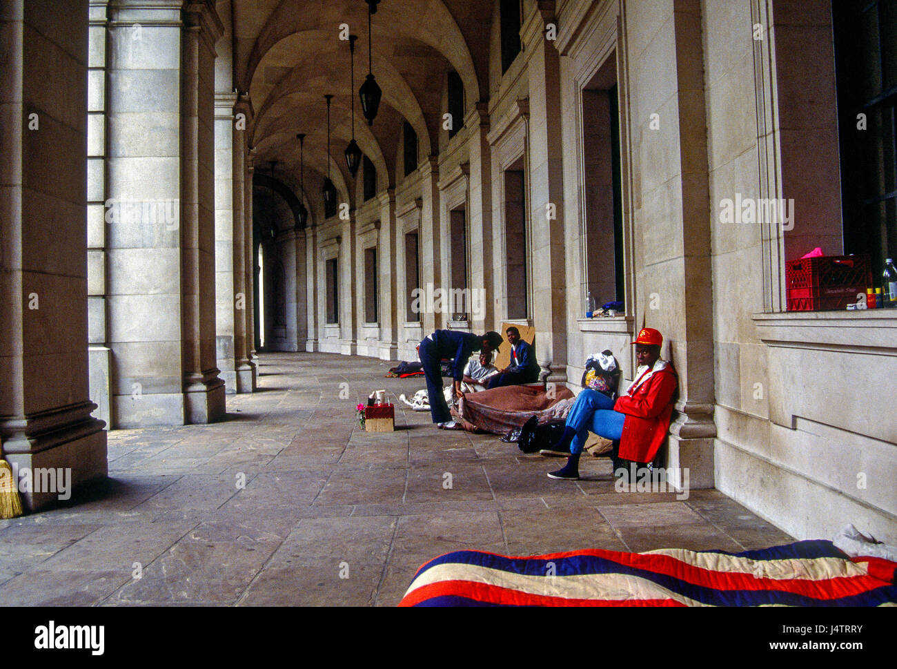 Homeless people lay sleeping on the sidewalk along the promenade arcade ...