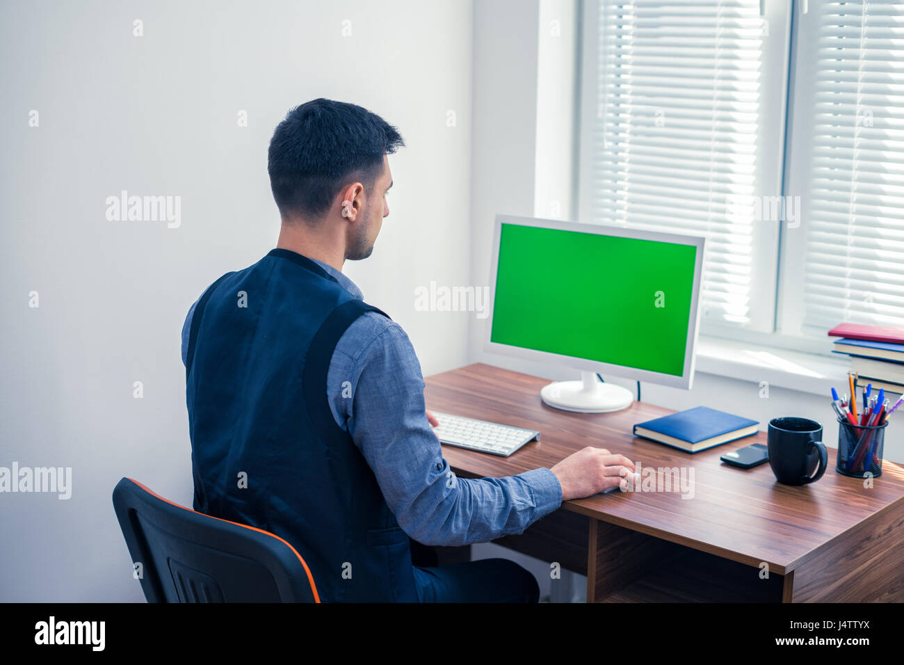 office worker sitting at computer with Chromakey on monitor Stock Photo ...