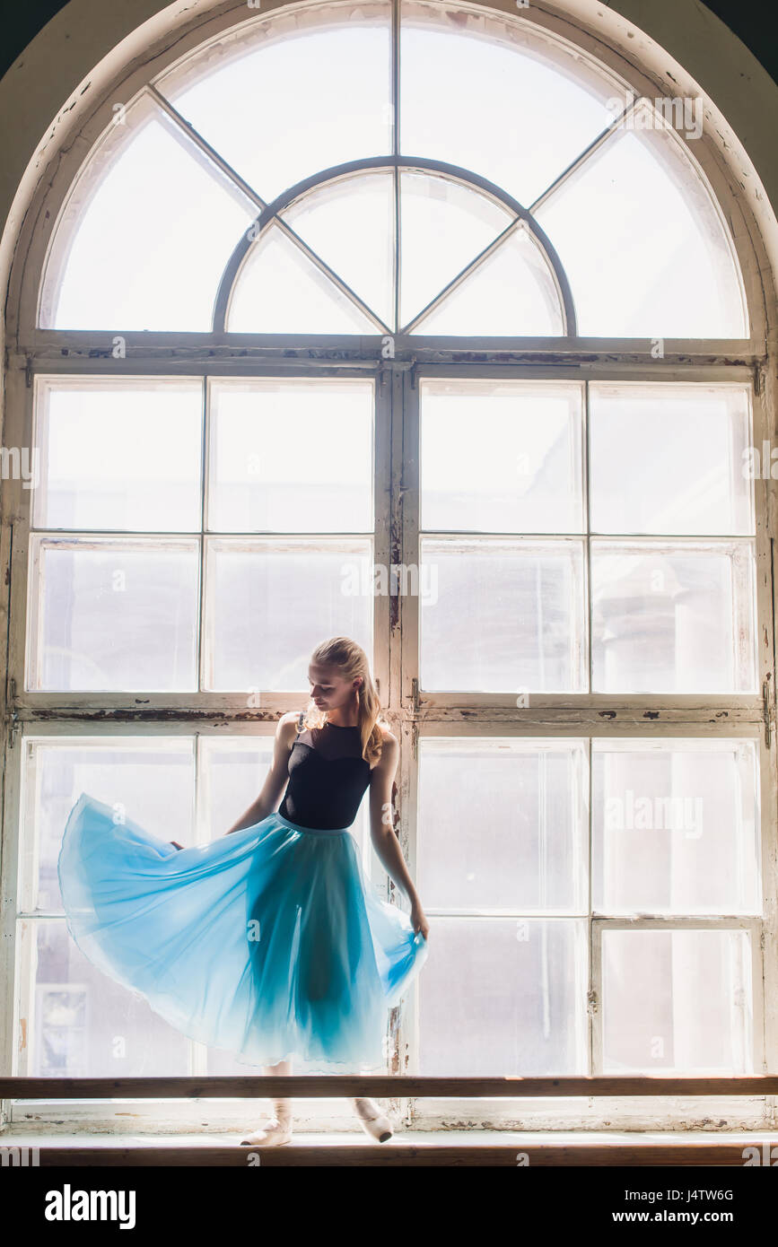 Ballerina dancing at window sill background. Girl in a turquoise ballet ...
