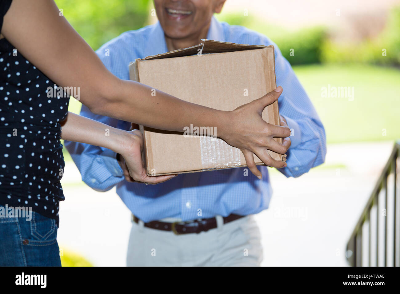 Closeup portrait of delivery man handing package to woman inside house ...