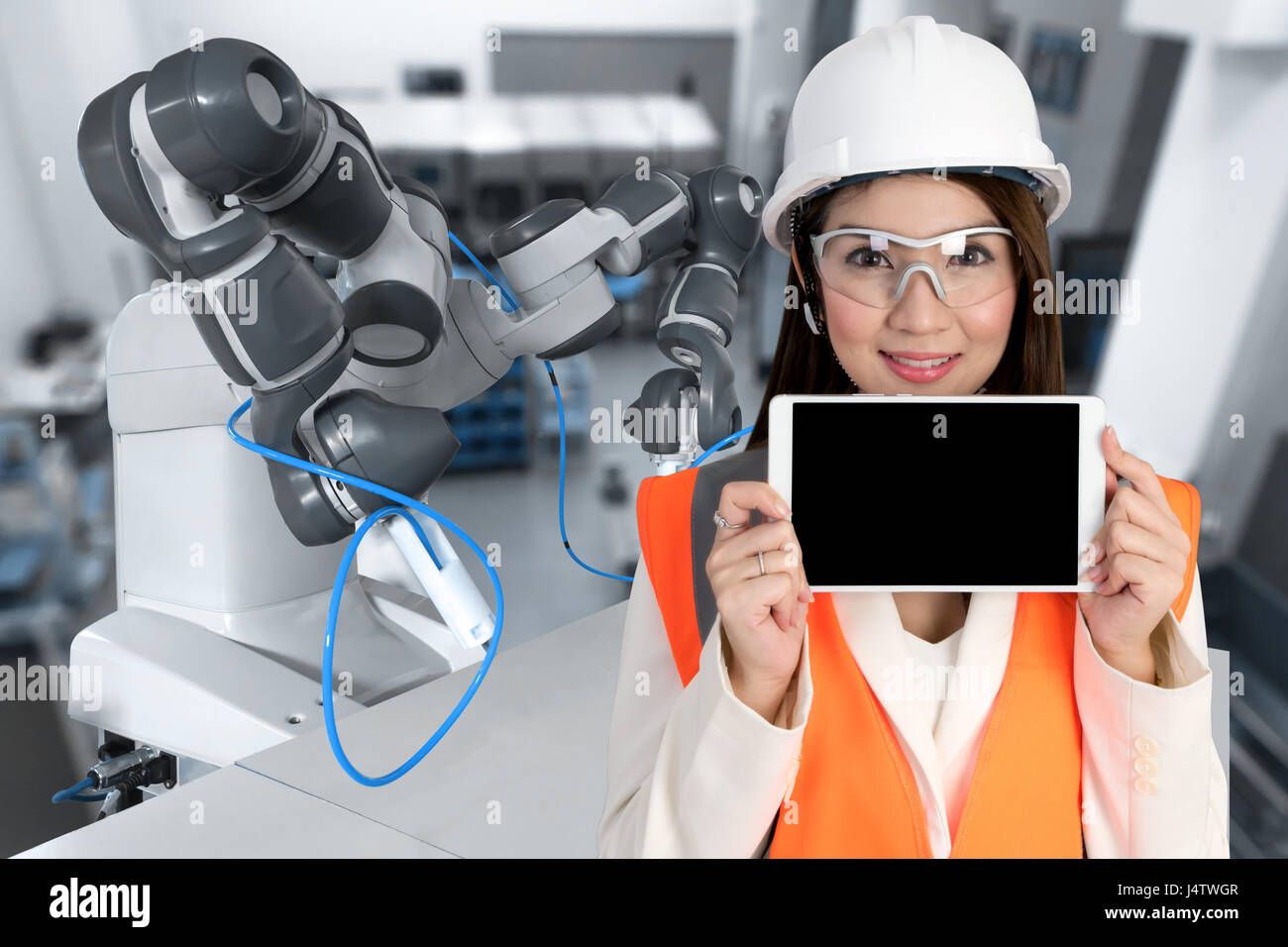 Smile young Asia female Engineer using tablet , wear glasses , automation robot arm machine in ...