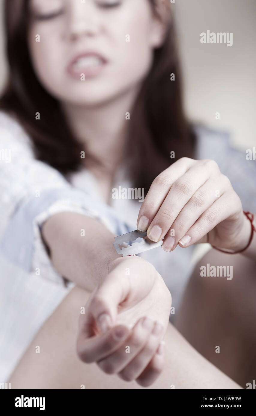 Young woman cuts veins on a hand on light background. Focus on hand ...