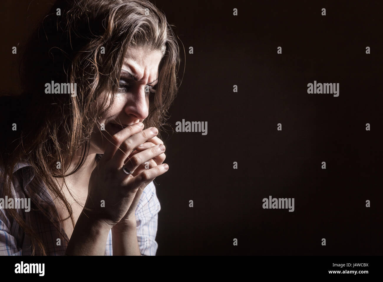 Young woman crying face in her hands on a dark background Stock Photo ...