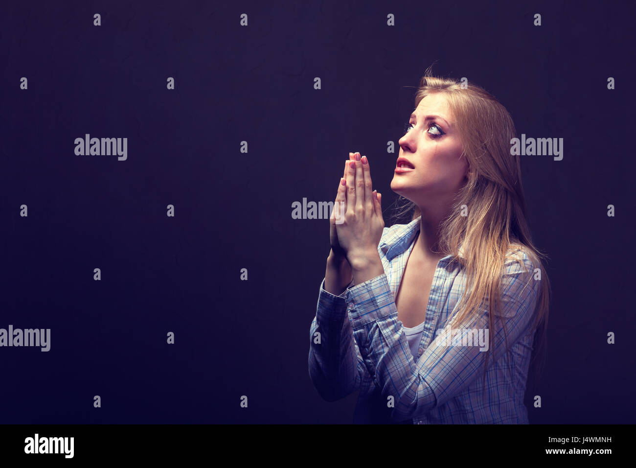 Young woman praying on a dark background Stock Photo - Alamy