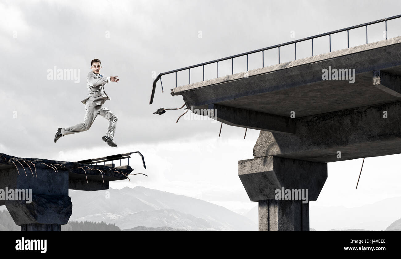 Determined businessman jumping over gap in broken bridge. Mixed media ...