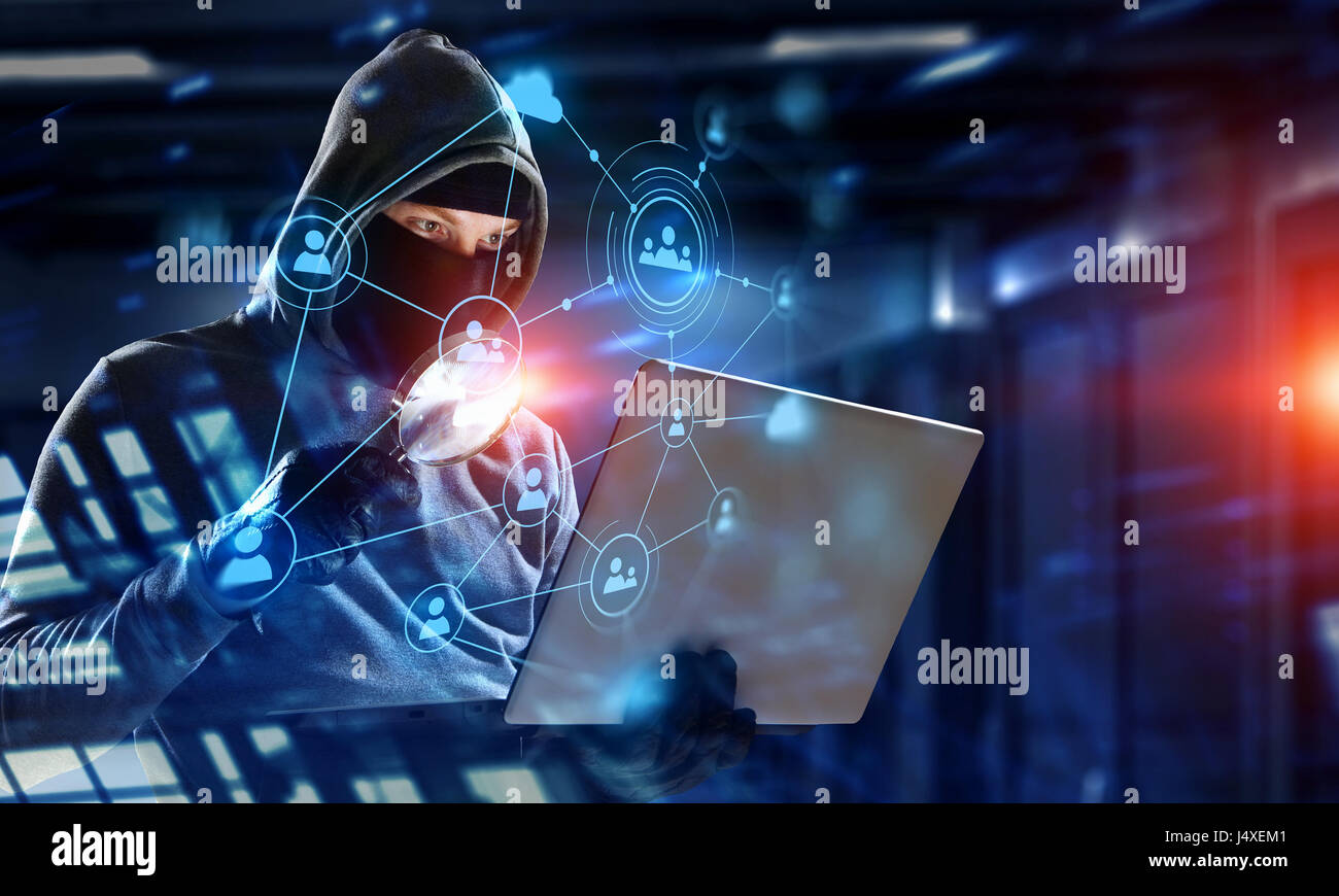 Computer hacker in hoodie and mask stealing data from laptop. Mixed ...