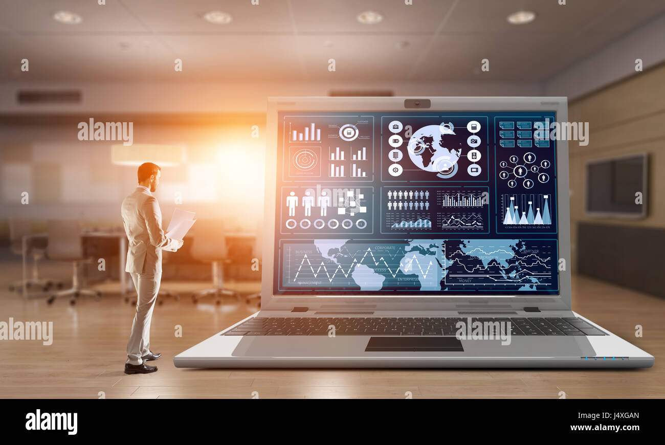 Young businessman and huge laptop with infographs on screen. Mixed ...