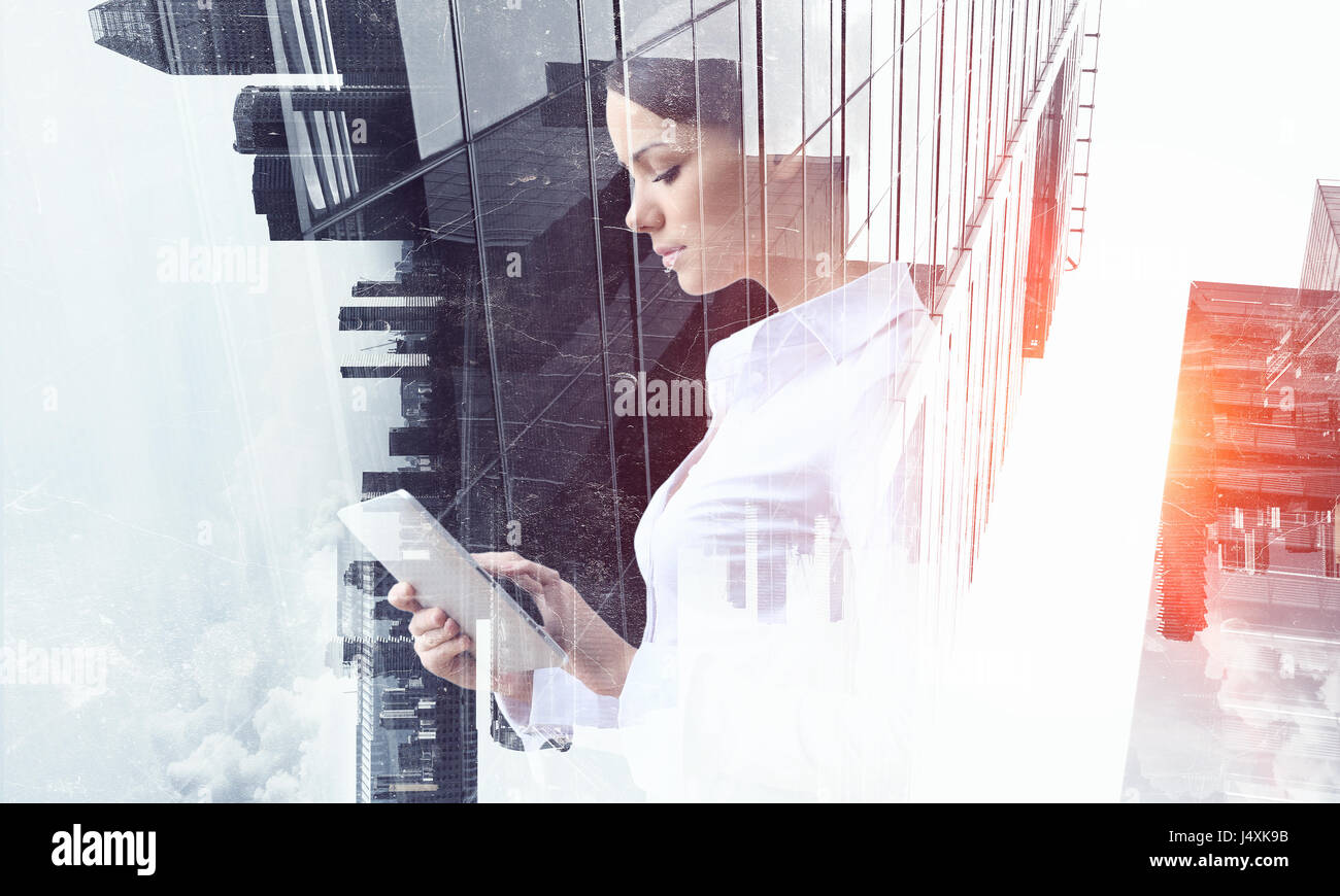 Attractive businesswoman using tablet pc against modern city background ...