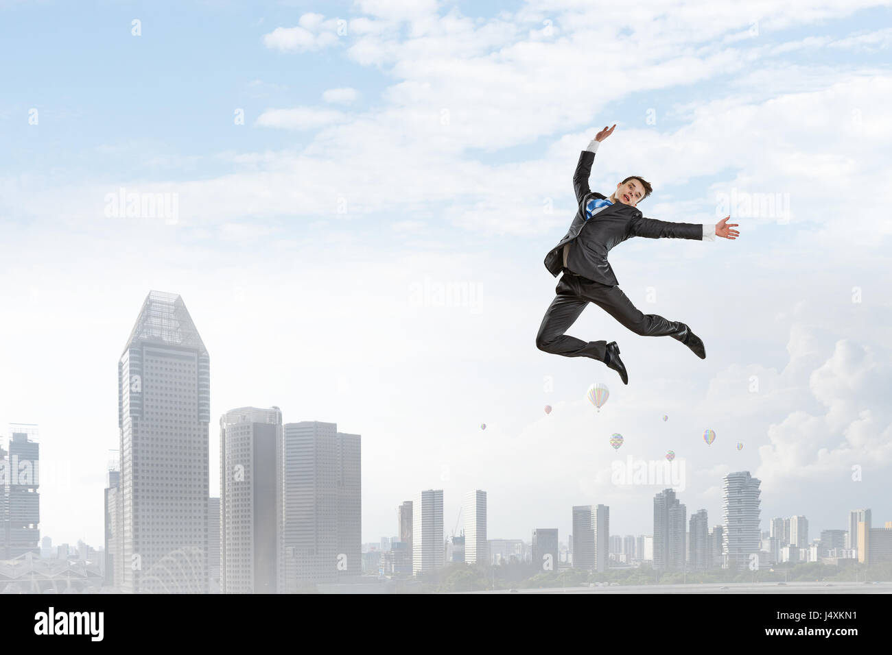 Happy businessman jumping high in sky to celebrate success Stock Photo ...