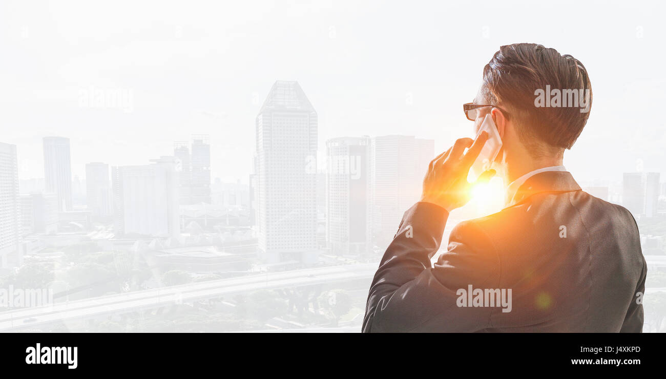 Back view of businessman against cityscape background talking mobile ...
