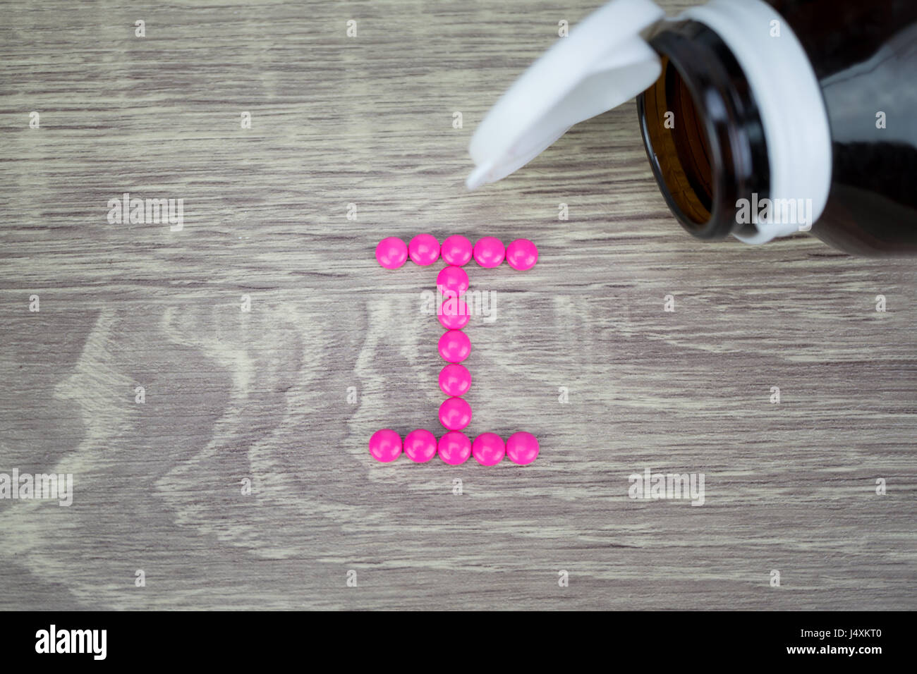 Pink pills forming shape to I alphabet on wood background Stock Photo ...