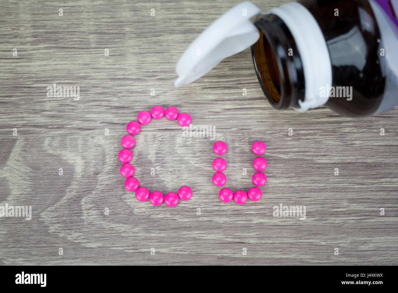 Pink pills forming shape to Cu alphabet on wood background Stock Photo ...