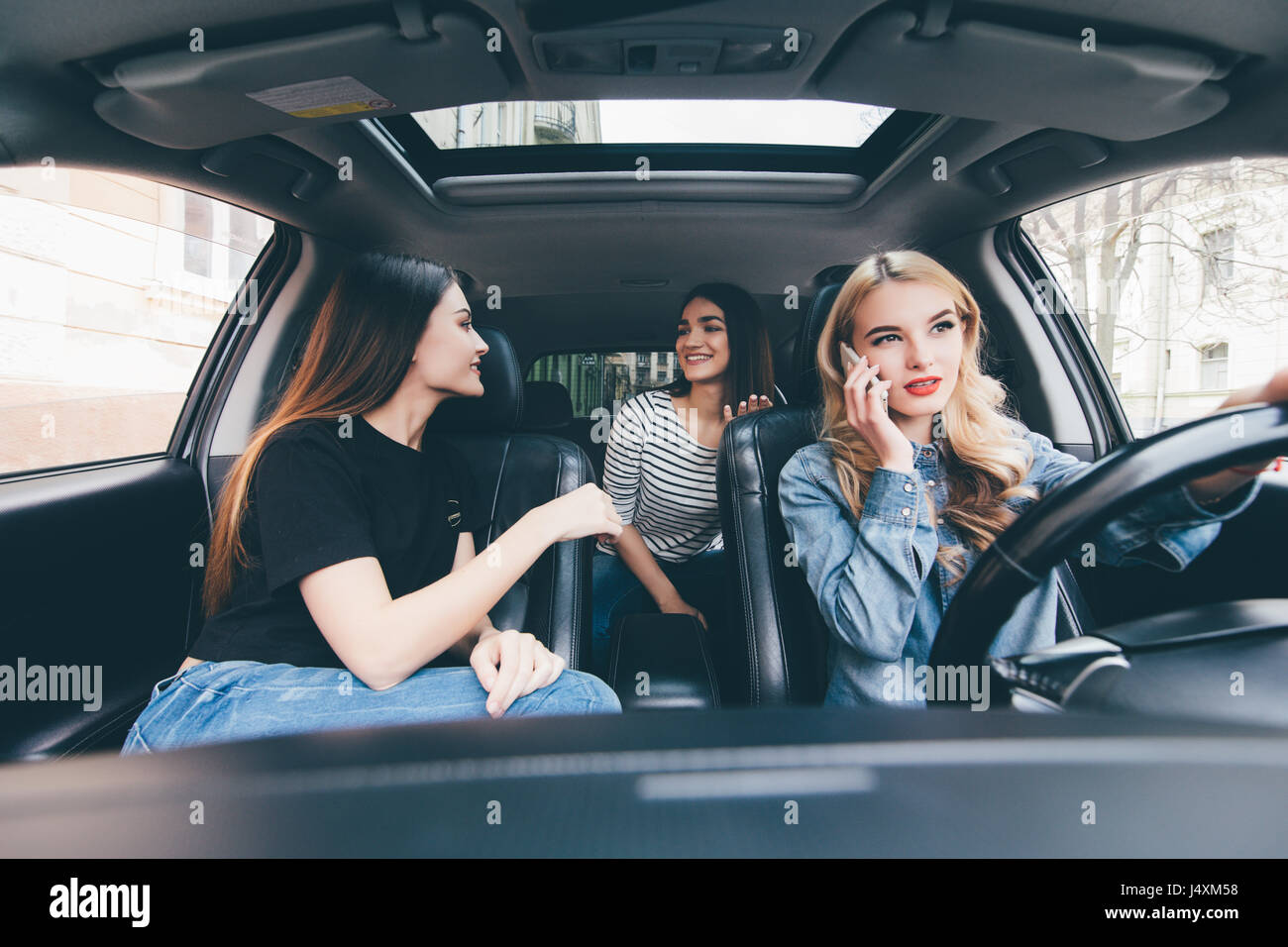 Two young women friends talking together in the o car as they go on a ...