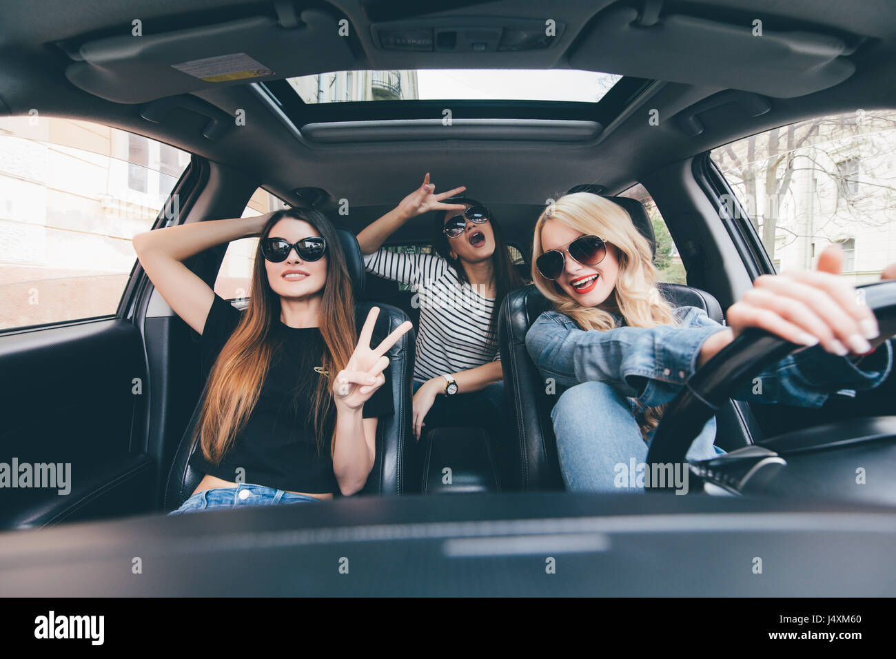Group of friends having fun on the car. Singing and laughing in the ...
