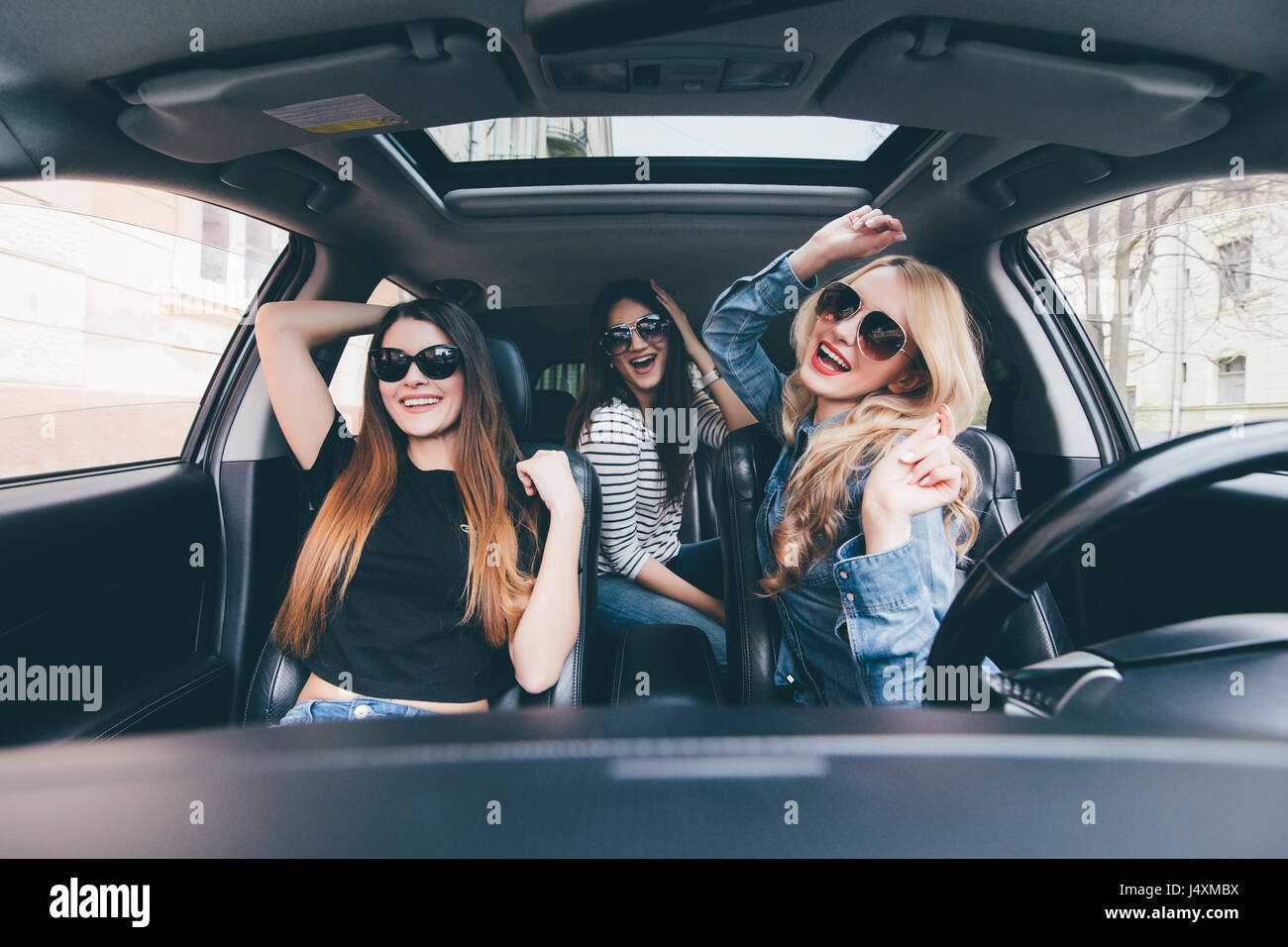 three girls driving in a convertible car and having fun Stock Photo - Alamy