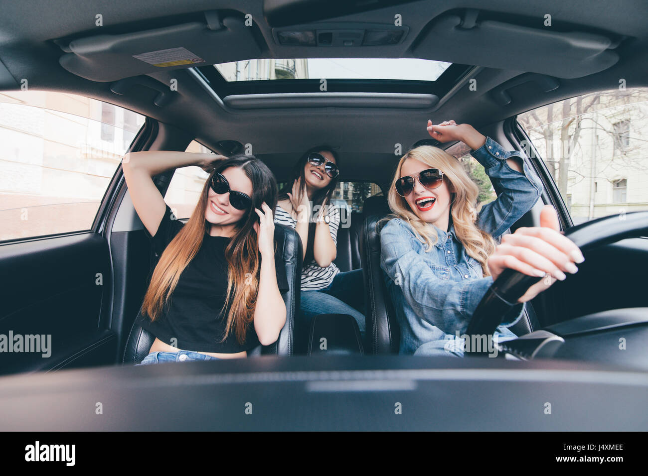 three girls driving in a convertible car and having fun Stock Photo - Alamy