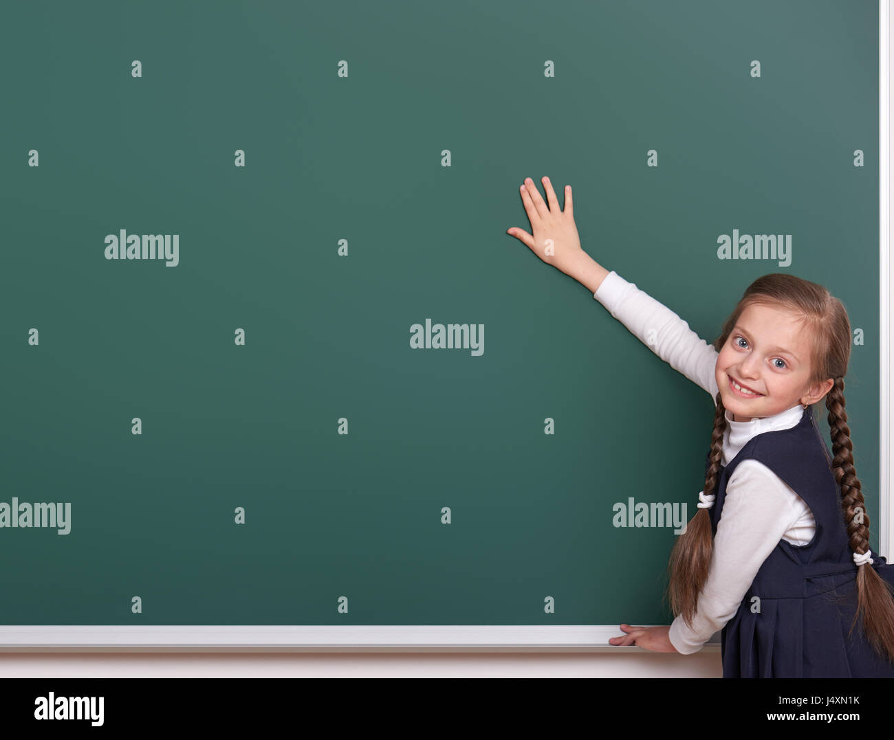 elementary school girl put hands on chalkboard background and show ...