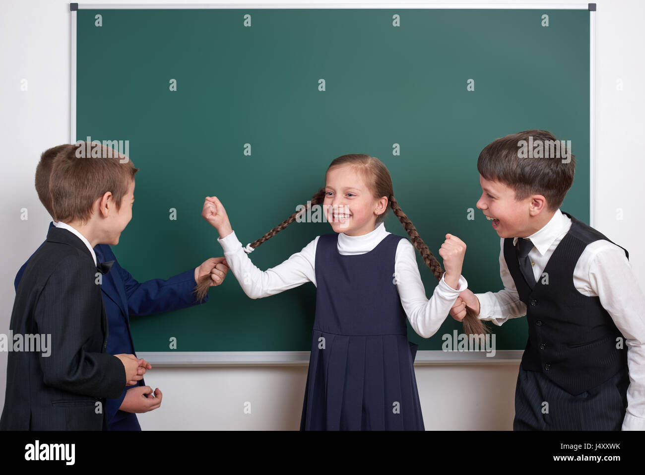 child play and having fun, boys pull the girl braids, near blank school ...