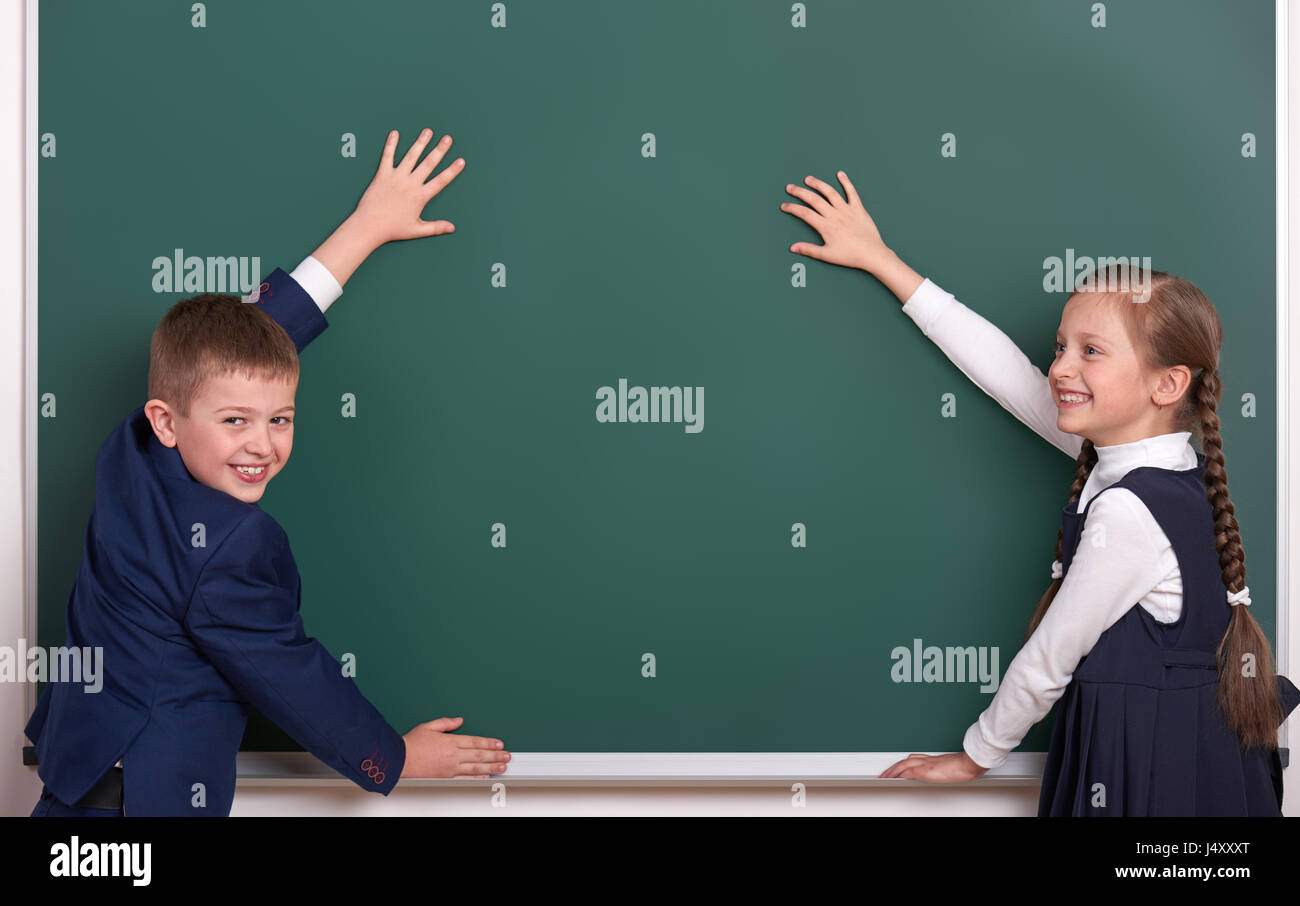 elementary school boy and girl put hands on chalkboard background and ...