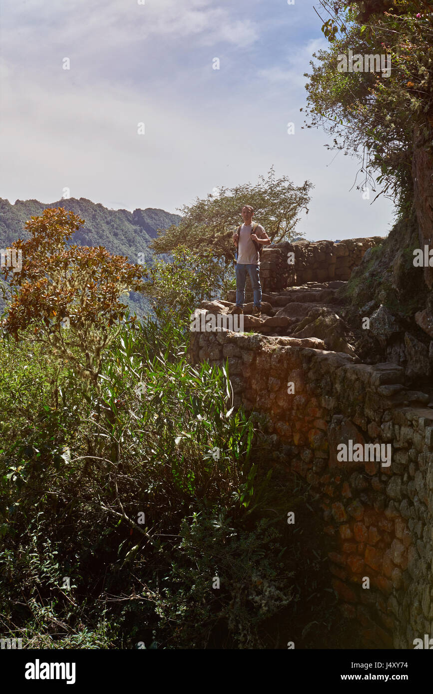 Man stand on stone path trail edge with backpack. Young man stand on ...