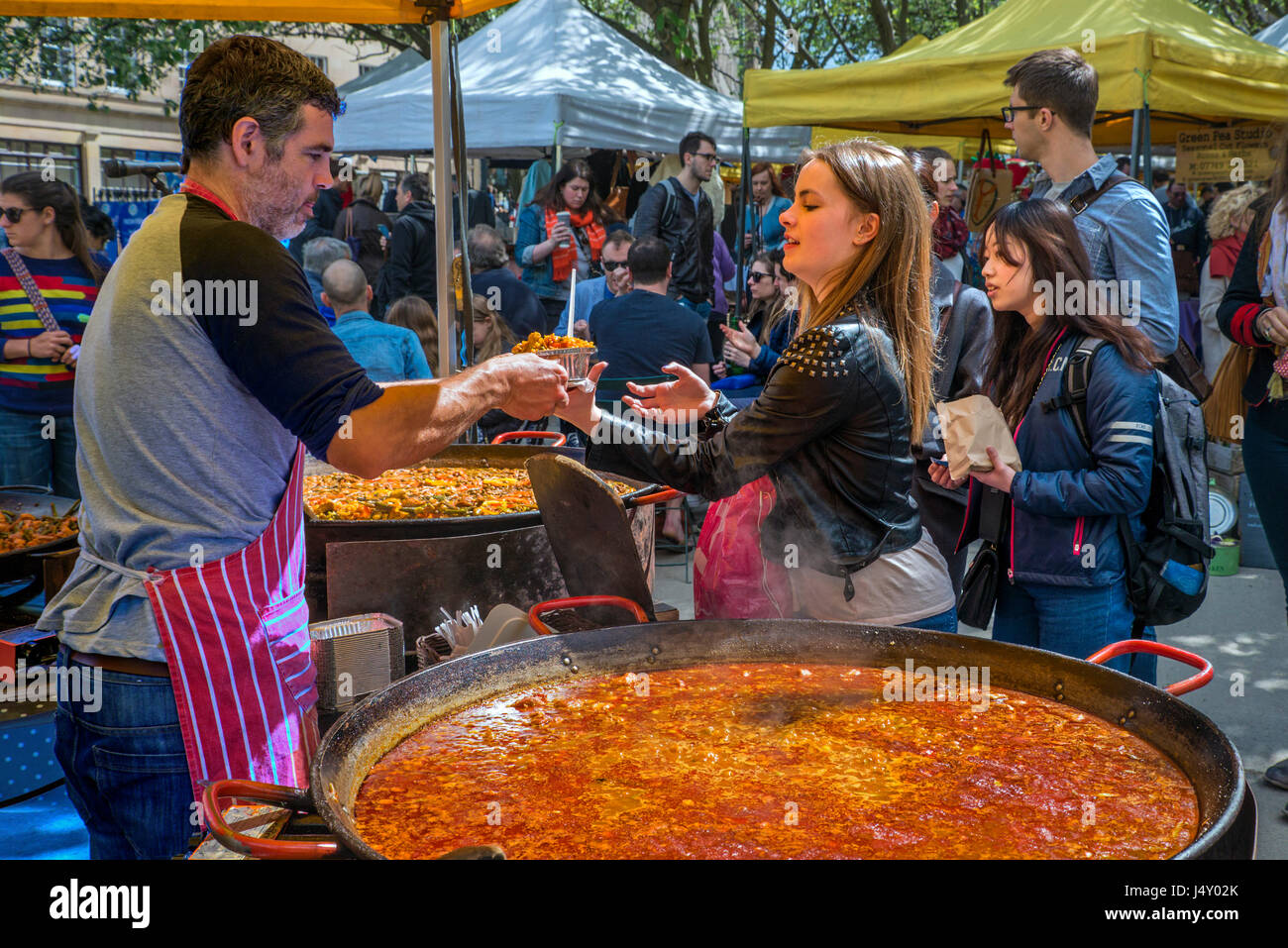 A young woman buys paella from a stall in Stockbridge Sunday market ...
