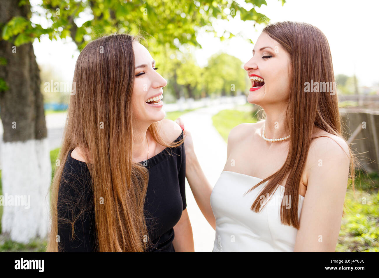 Two laughing ladies in cocktail dress standing outdoors. Young ...