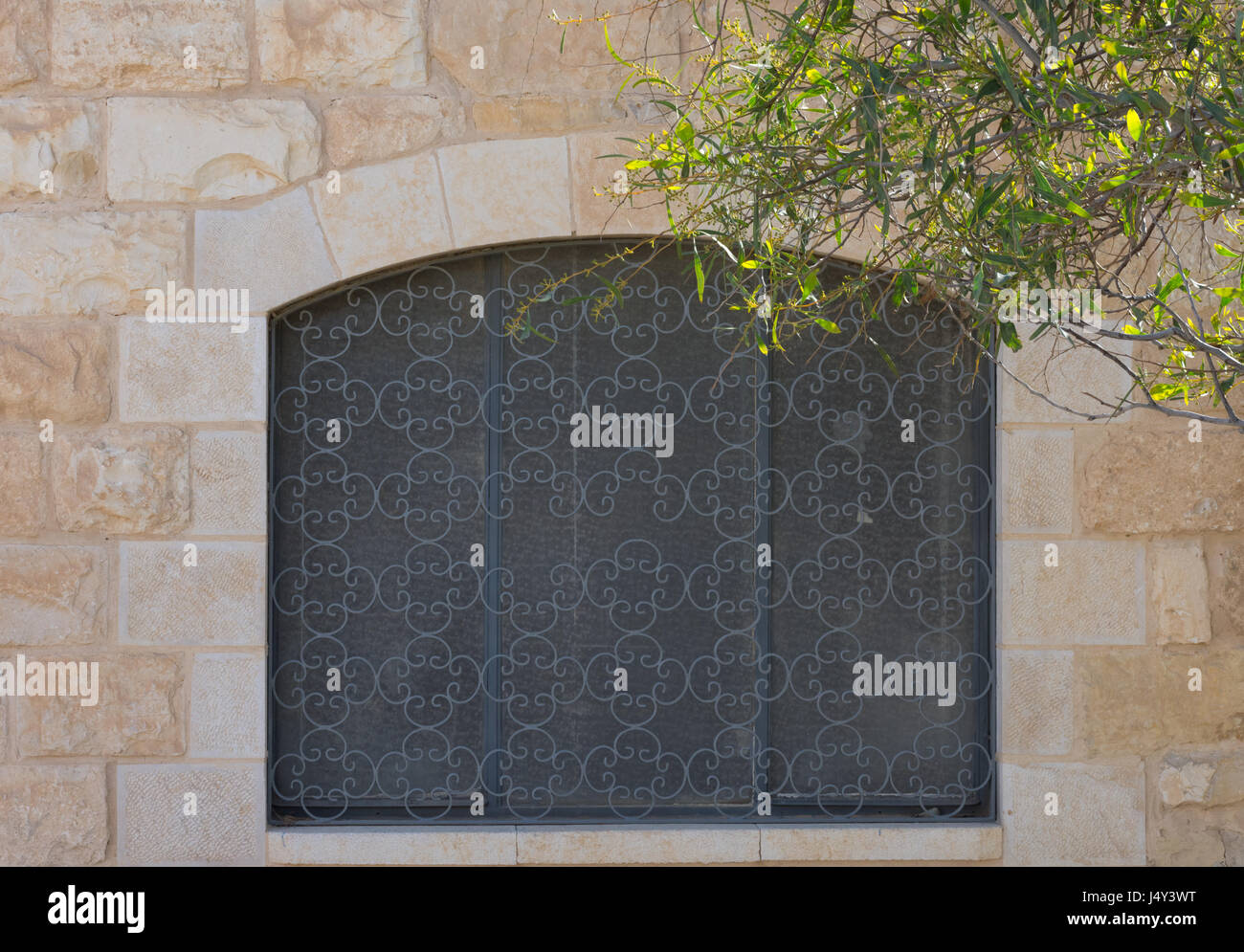 Arched window with decorative metal screen in a building made from hewn ...