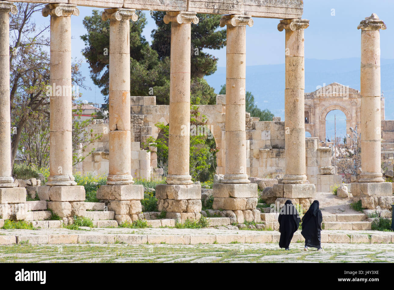 A pair of Muslim woman walking in an ancient colonnade of the Jerash ...