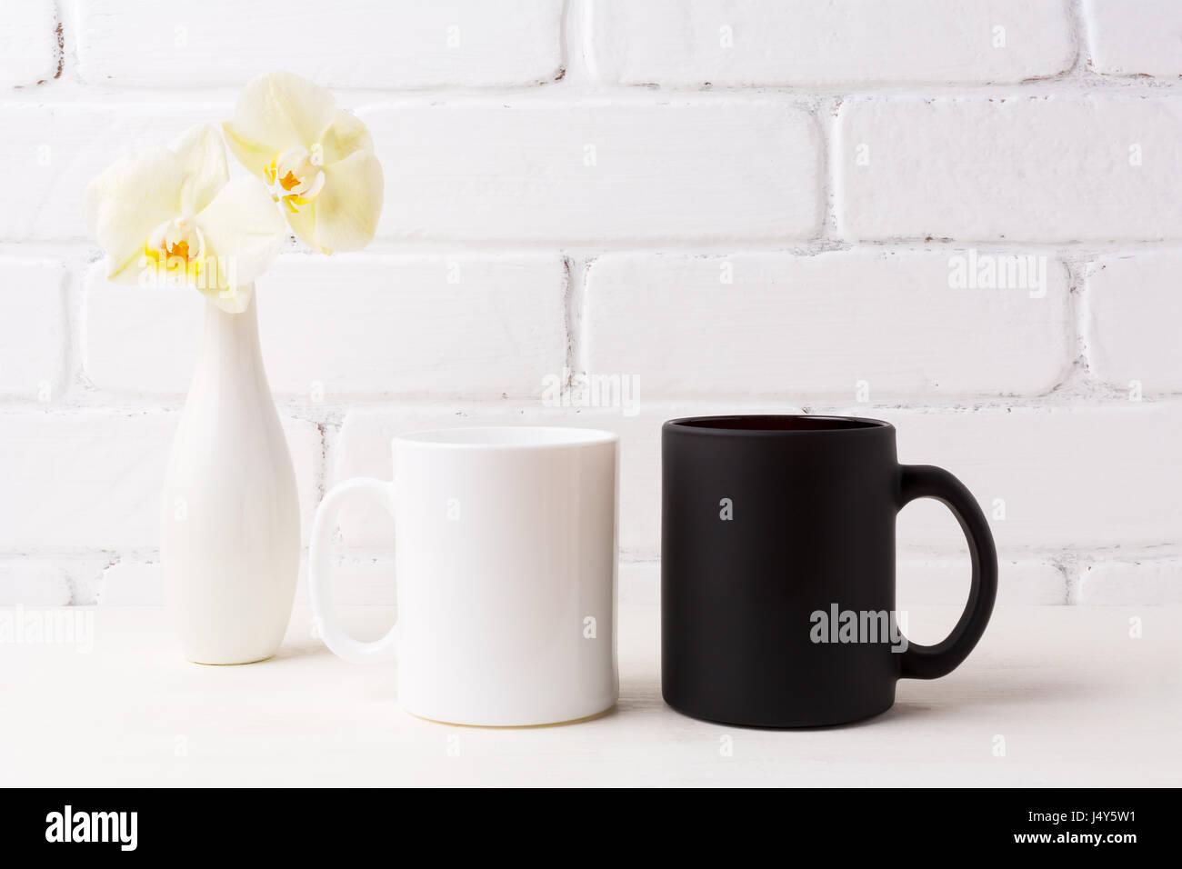 White and black coffee mug mockup with soft yellow orchid in vase ...