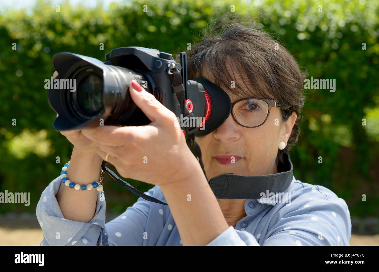 A mature woman using a camera dslr Stock Photo - Alamy